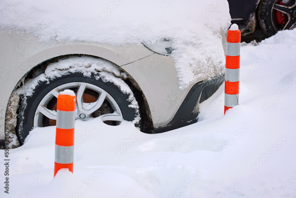 Parking posts placed at snowy parking stall. Car parked close to red ...
