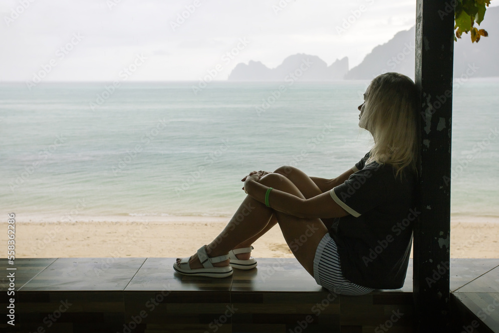 Portrait of mutely woman sitting on the terrace and thinking, sea rainy ...