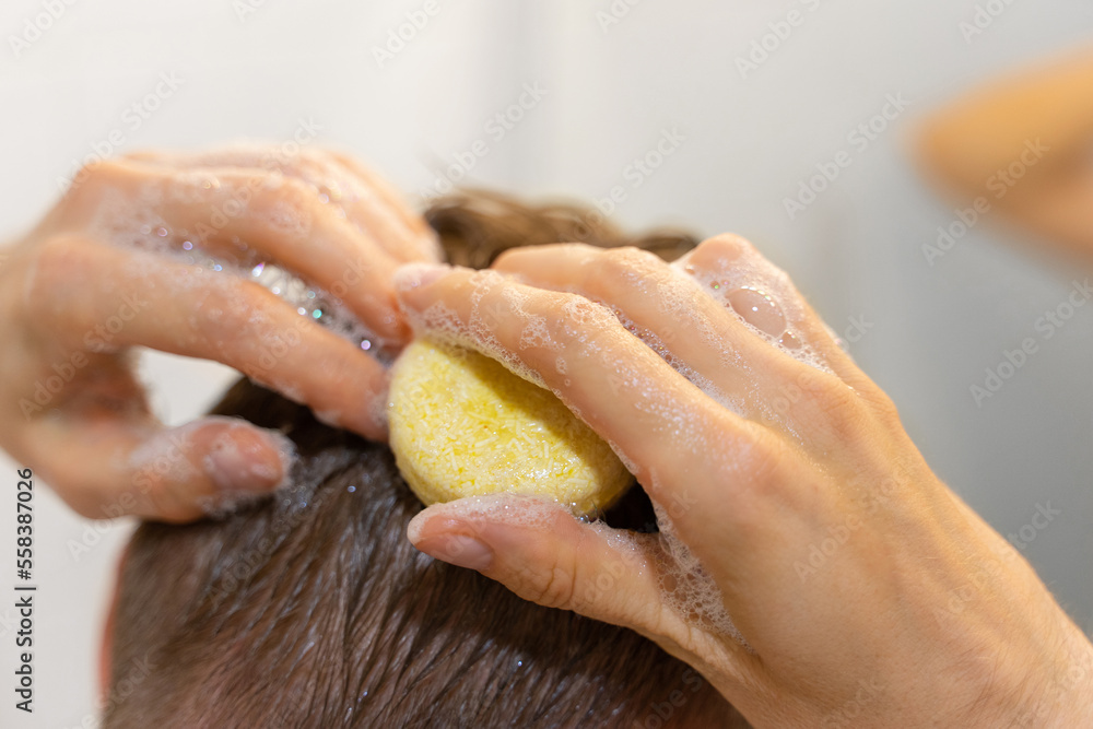 A man uses a solid shampoo bar in the bathroom. An applying shampoo to ...