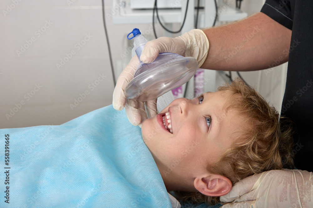 Courageous boy smiles and looks at the doctor before the operation on ...