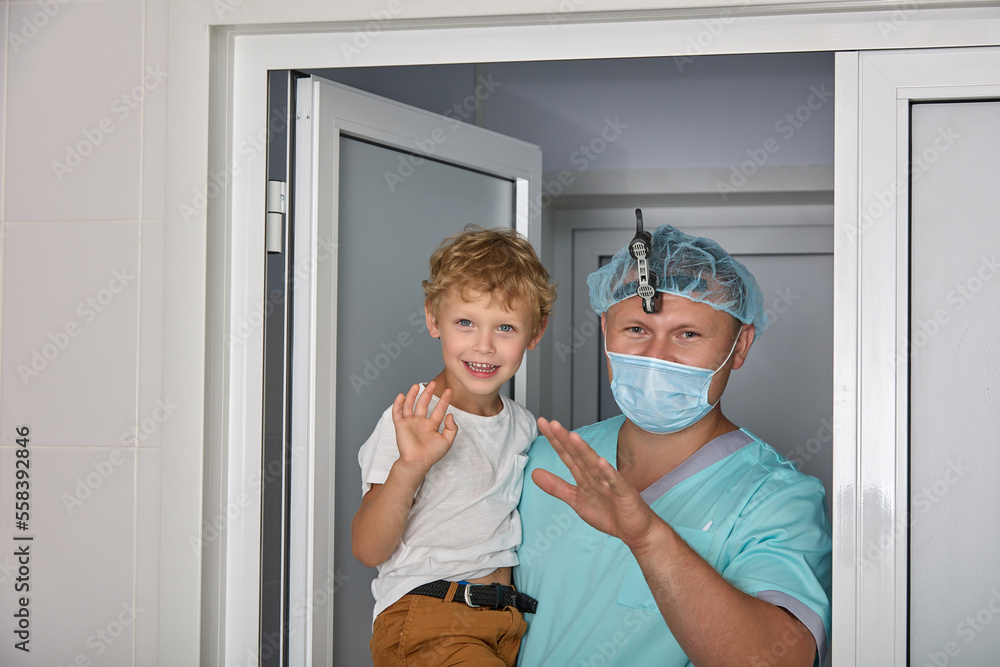 Foto de Funny boy in white T-shirt in arms of experienced pediatric ...