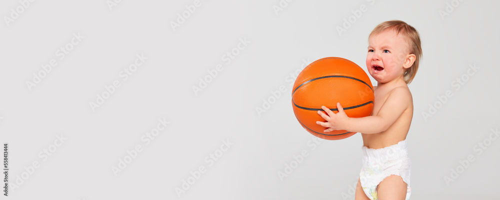 Crying baby with big basketball ball. One little cute toddler girl ...
