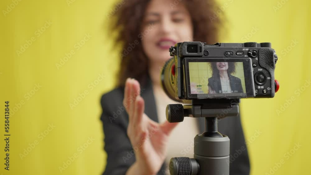 Close-up screen of video camera with smiling Caucasian woman adjusting ...
