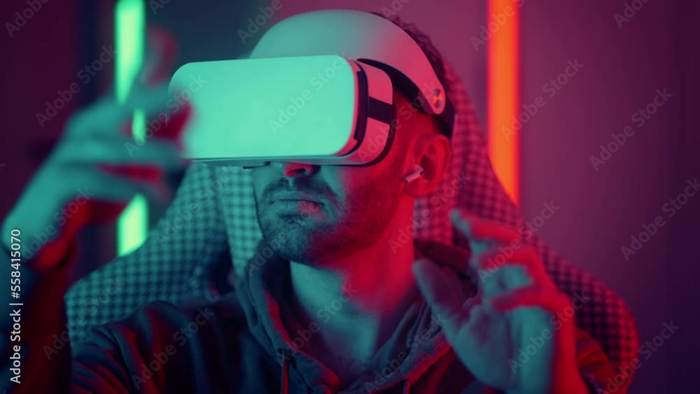 Cyber gamer in VR glasses plays virtual reality game in neon futuristic ...