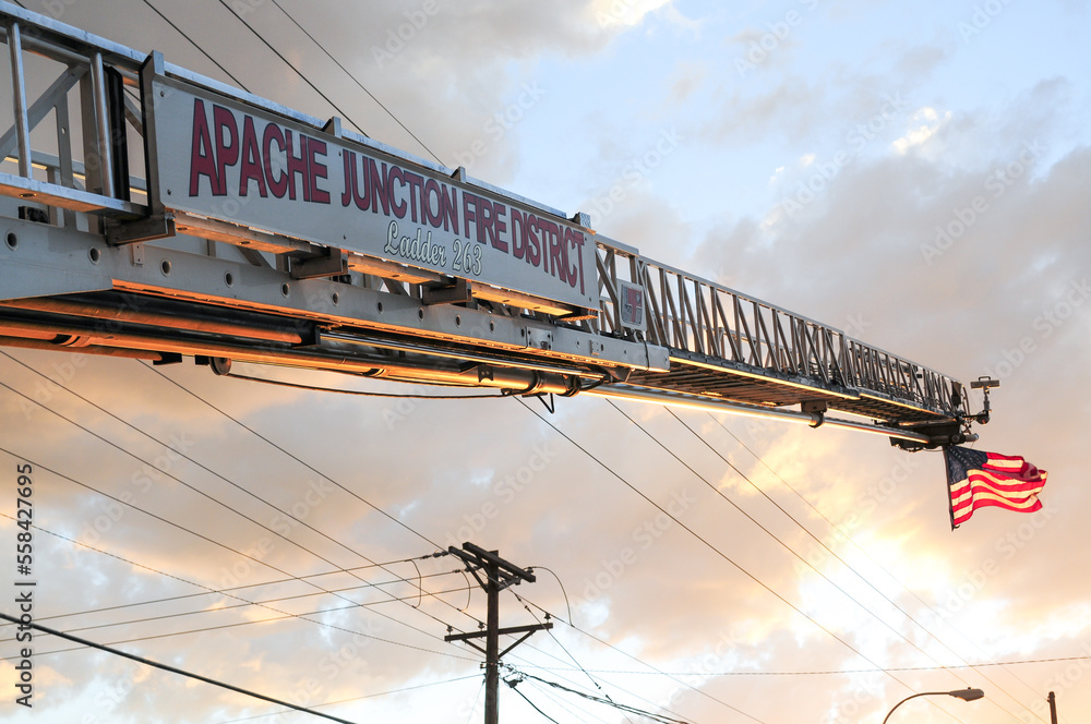 Extended aerial ladder of a fire truck with an American flag attached ...