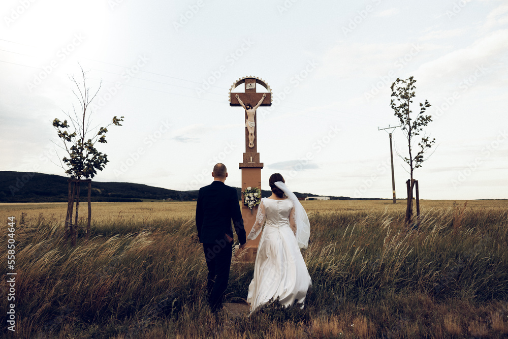 bride and groom holding hands in front of jesus christ statue during ...