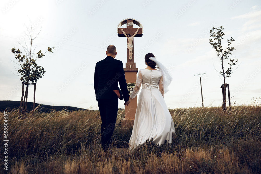 bride and groom holding hands in front of jesus christ statue during ...