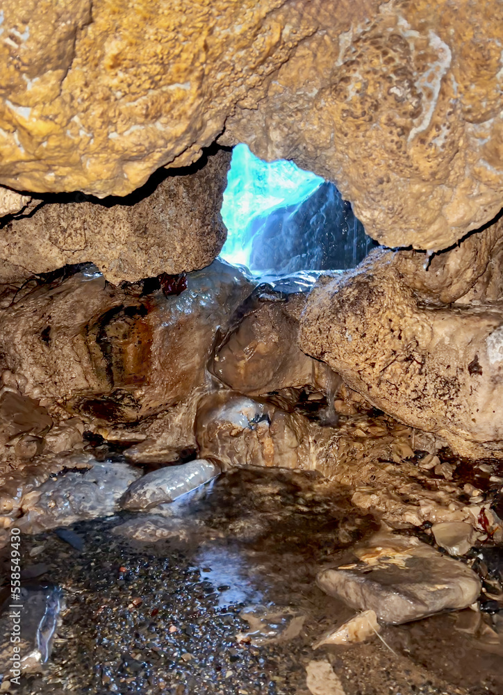 Inside a small cave with a hole in the wall showing the waterfall ...