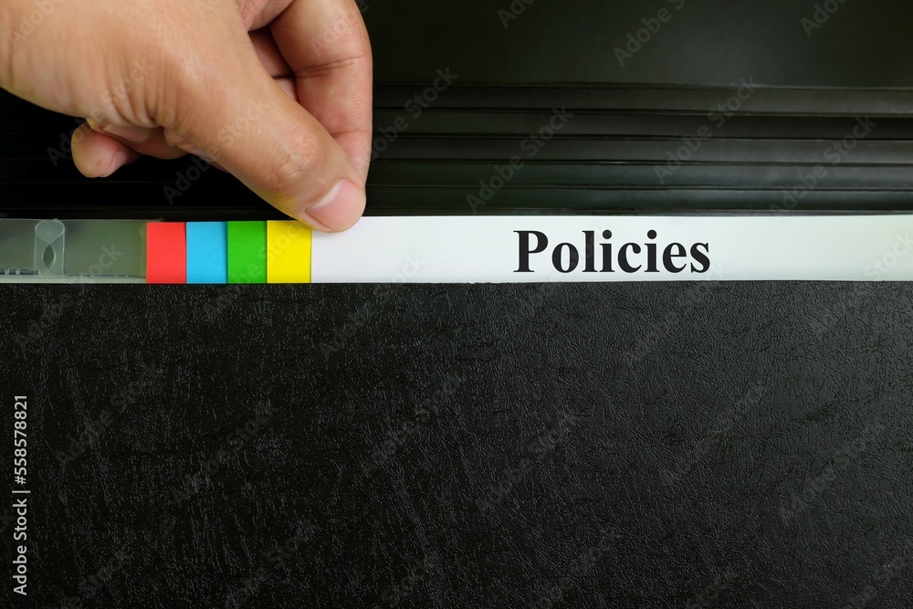 Hand picking policies file record in black binder folder. Company and ...