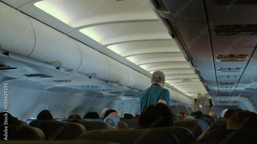 Man walking down the isle on an Airbus Airliner cabin in flight - back ...