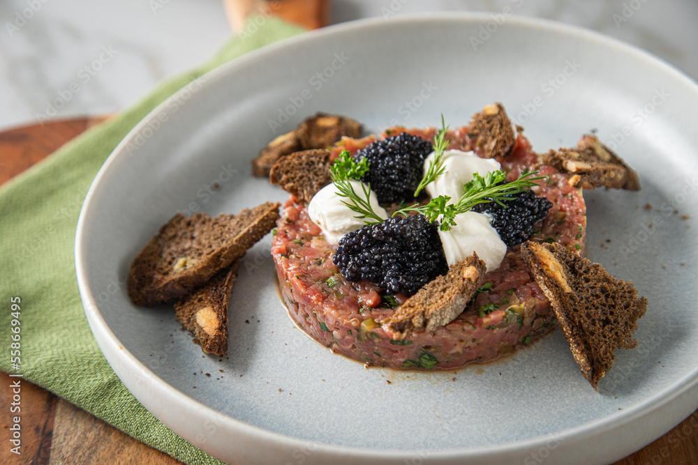 Tatar roh vom Rind mit schwarzen Kaviar, Schmand, Dill und Brot als ...