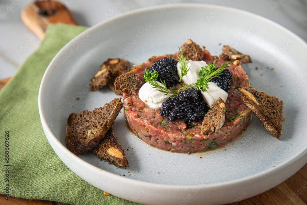 Tatar roh vom Rind mit schwarzen Kaviar, Schmand, Dill und Brot als ...
