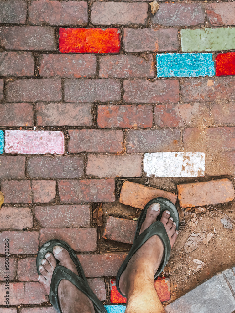 Feet of man wear sandals on old beautiful multicolor bricks paving ...