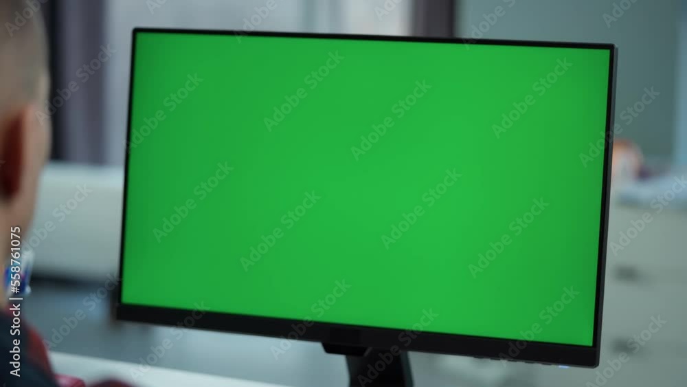 Young Man Working At Computer With Green Mock Up Screen Sitting At Desk ...
