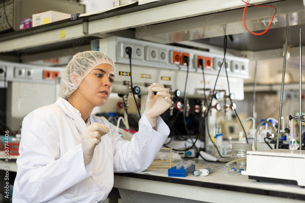 Concentrated young woman checking reagent reaction in test tube during ...