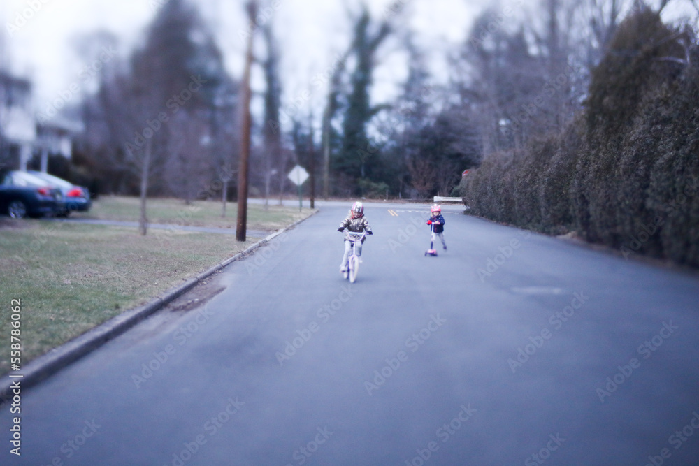 little girls playing outside riding bike and scooter on street Stock ...