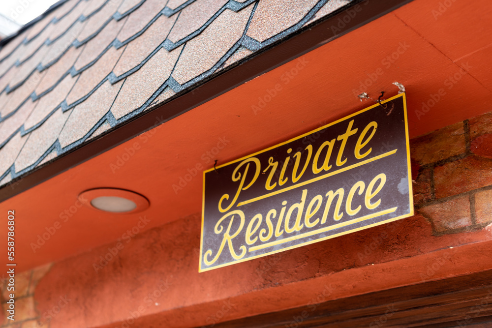 A private residence sign hanging from the eave of a bright orange ...
