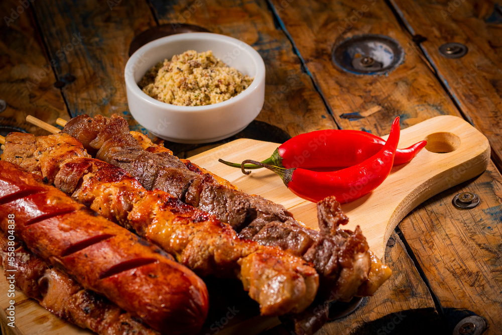 Espetinhos de churrasco em tábua de madeira com acompanhamentos, arroz ...