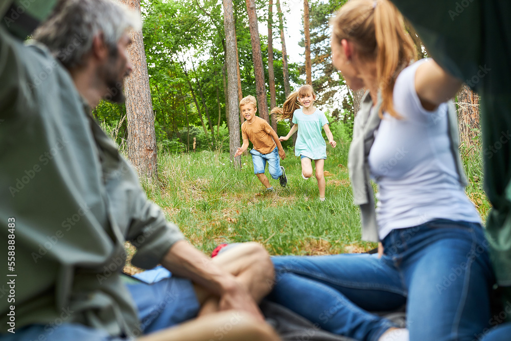 Happy children running towards parents sitting in tent Stock Photo ...