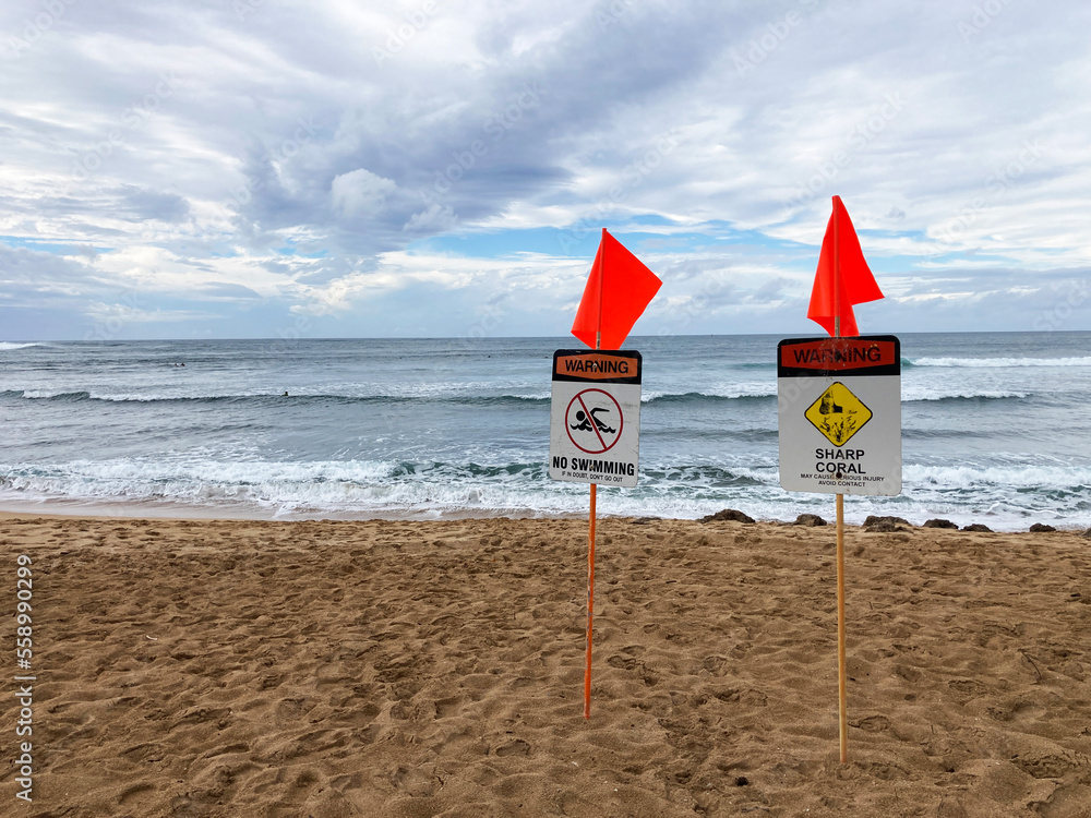 Two warning signs, sharp coral, no swimming and red warning flags ...