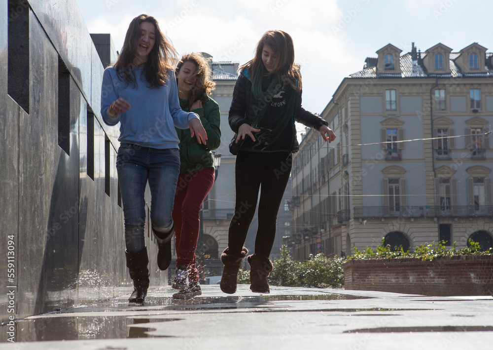 Teen girls splash through rain puddles in urban setting Stock Photo ...