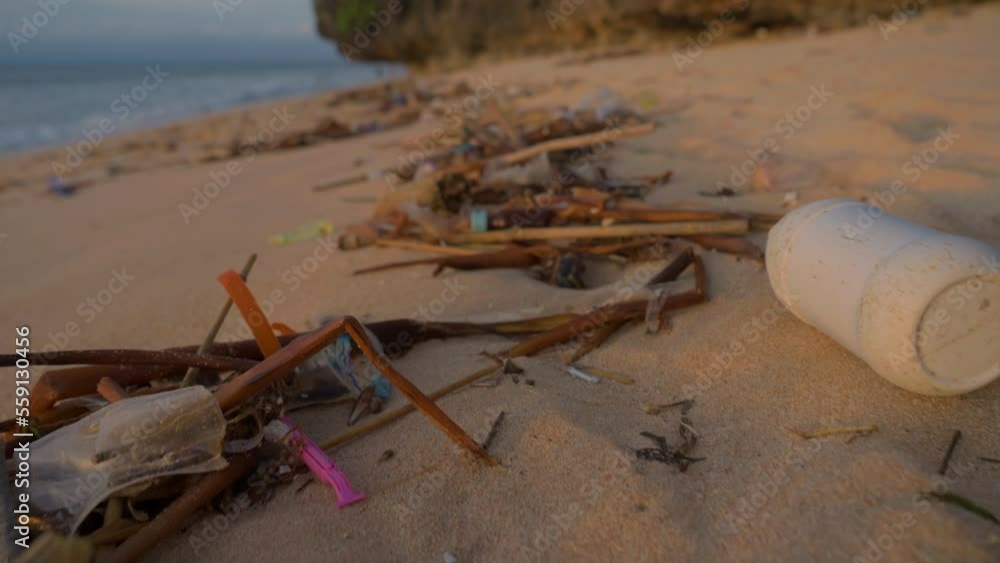 Close-up slow motion video of plastic trash on wild sand beach in ...