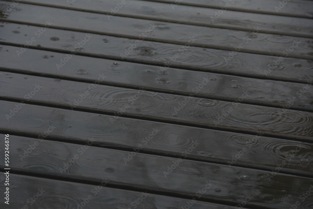 Rain falling on wet wooden deck boards, raindrops splashing on decking ...