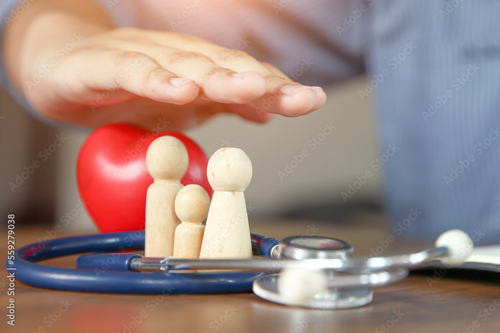 Doctor hand protect wooden doll with heart and stethoscope concept of ...