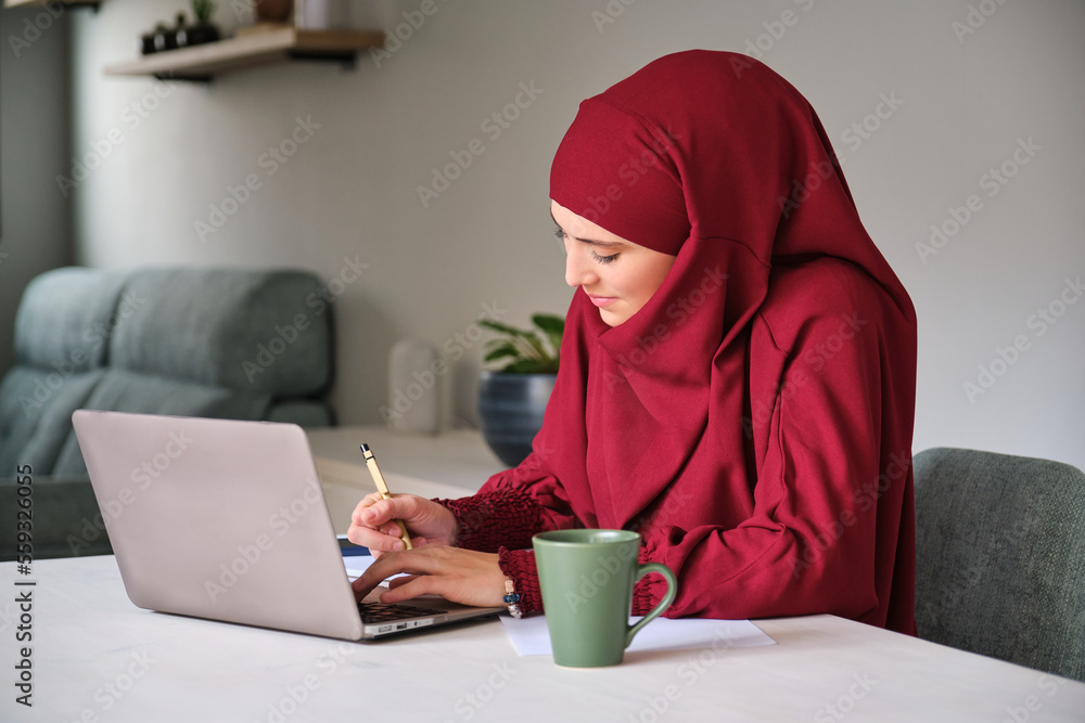 Muslim young woman university student in hijab using the laptop at home ...
