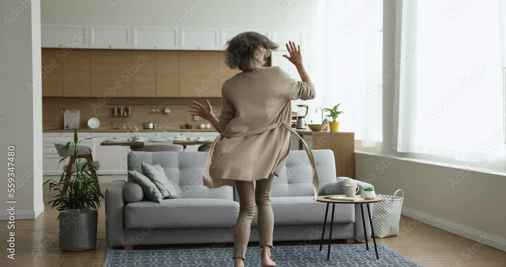 Full-length view attractive barefoot mature woman dancing in living ...