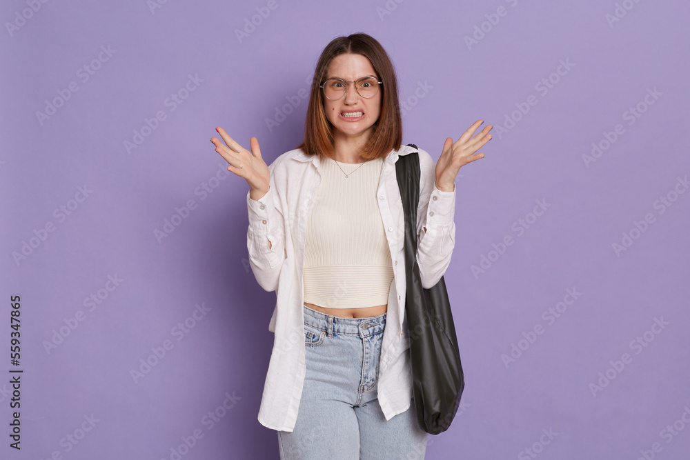 Horizontal shot of angry shocked woman wearing stylish clothing holding ...