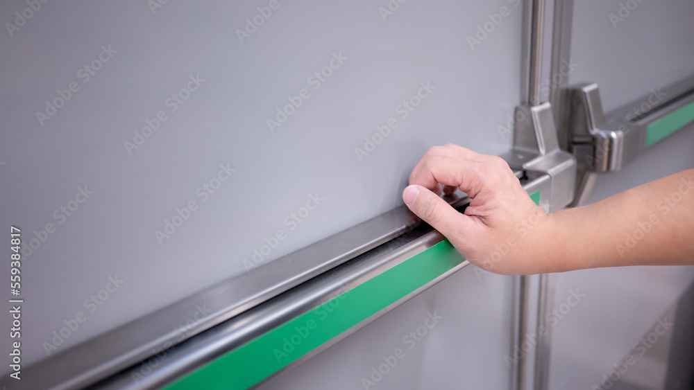 Male hand pushing stainless steel panic bar opening the emergency fire ...