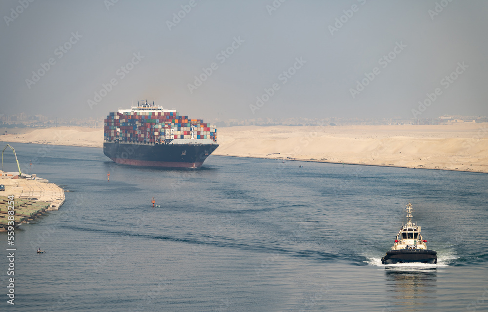The Suez Canal is a shipping canal in Egypt. Huge Cargo ship drives through Suez Canal. Stock ...