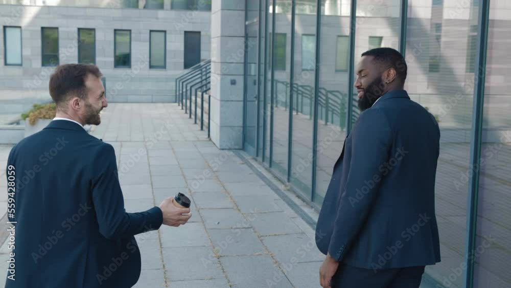 Two diverse office employers walking downtown during coffee break ...