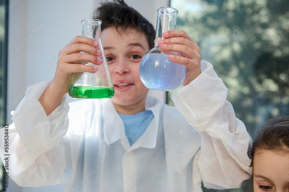 Details: selective focus on the hands of a schoolboy in white lab coat ...
