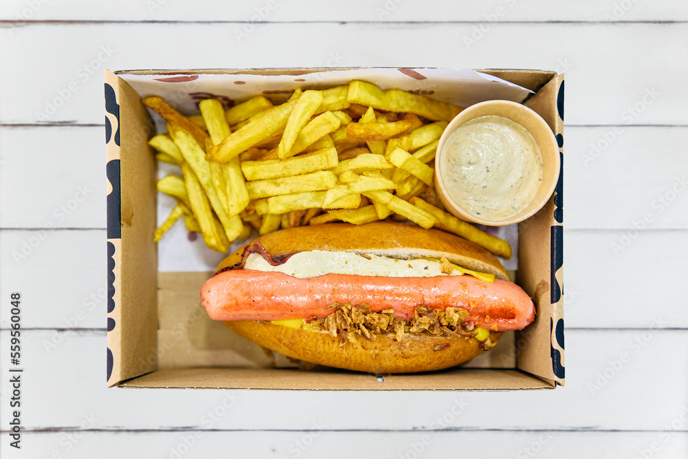 Hot dog menu, served in a cardboard box with fries and pickle ...