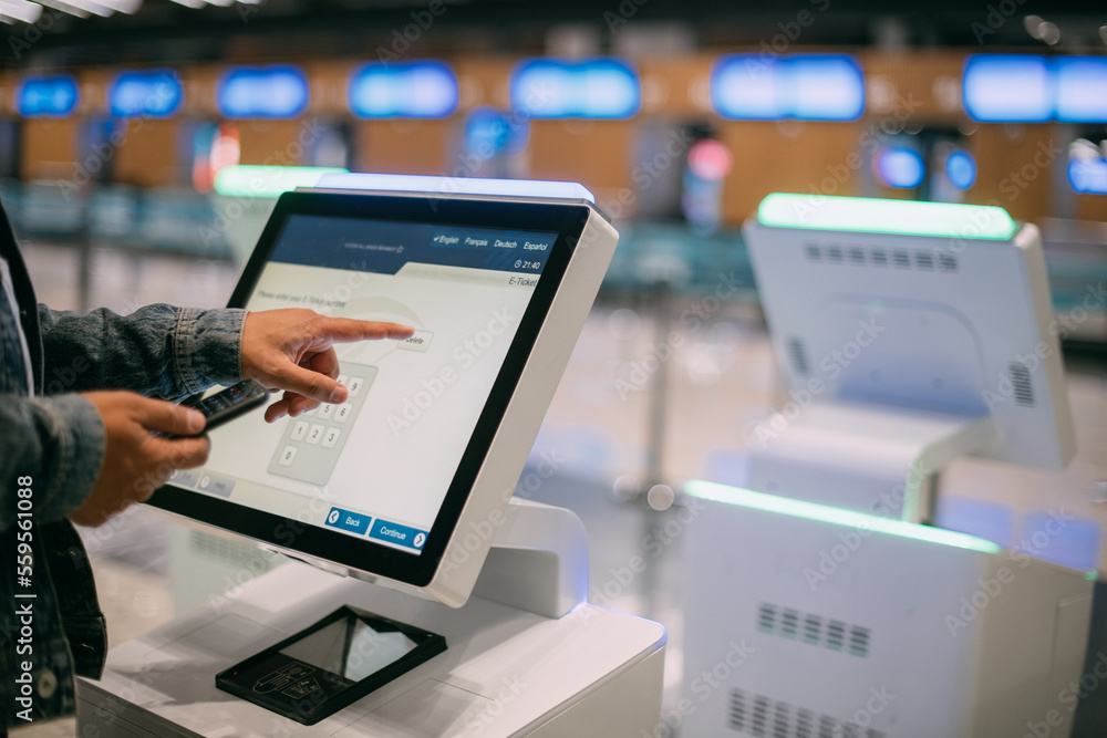 A male passenger at the electronic check-in desk in the departure area ...