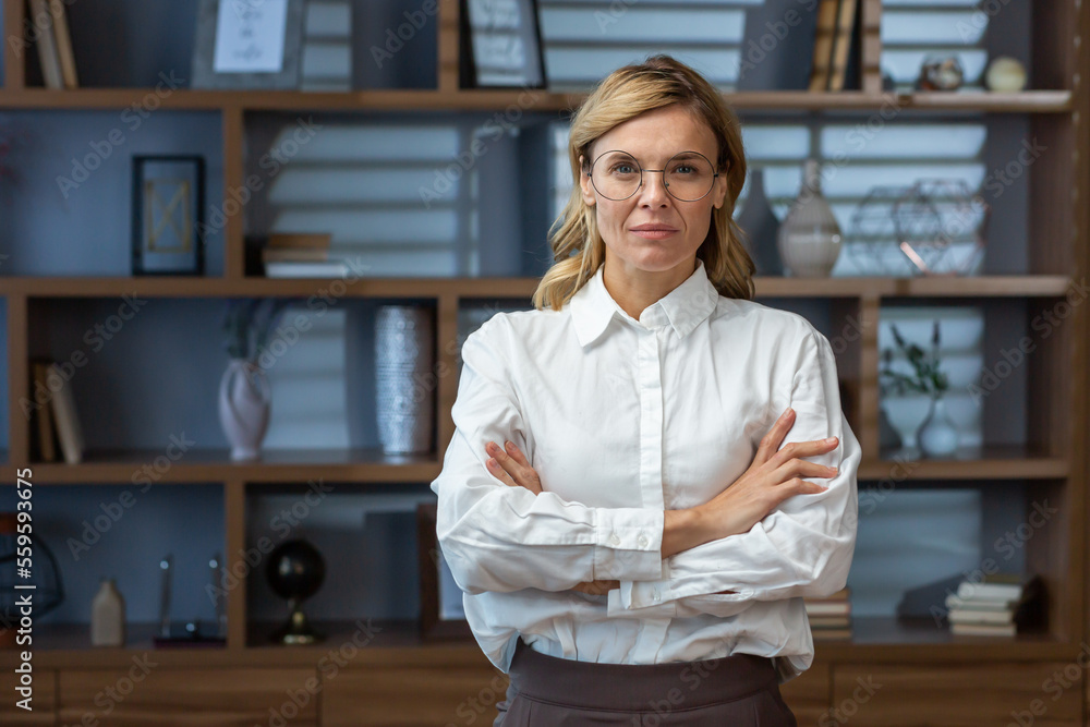 Portrait of senior serious female boss in classic office in the evening ...