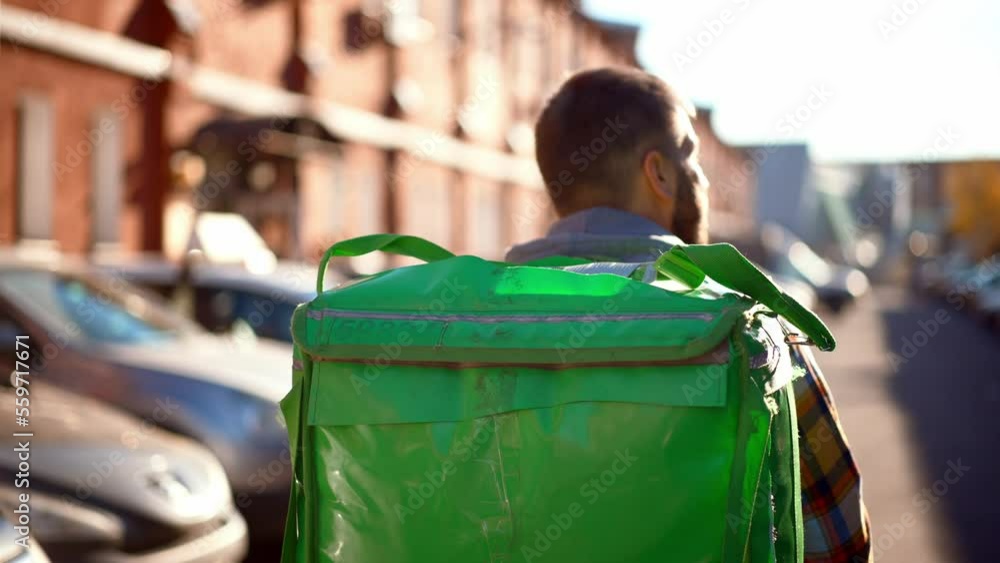Rear view of green backpack, box on shoulders courier from food ...