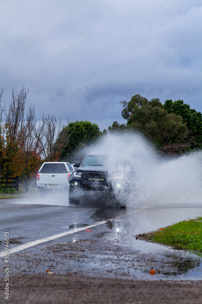 Flood water forming puddle on highway road through town with car ...