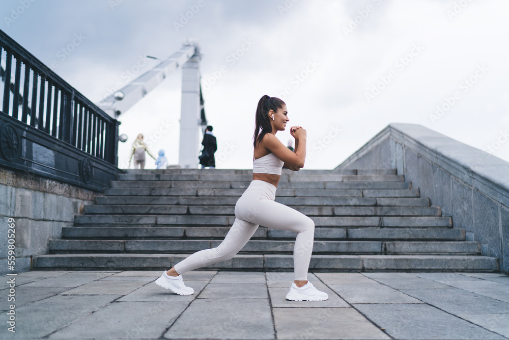 Young happy woman makes deep forward lunges to pump the muscles of the ...