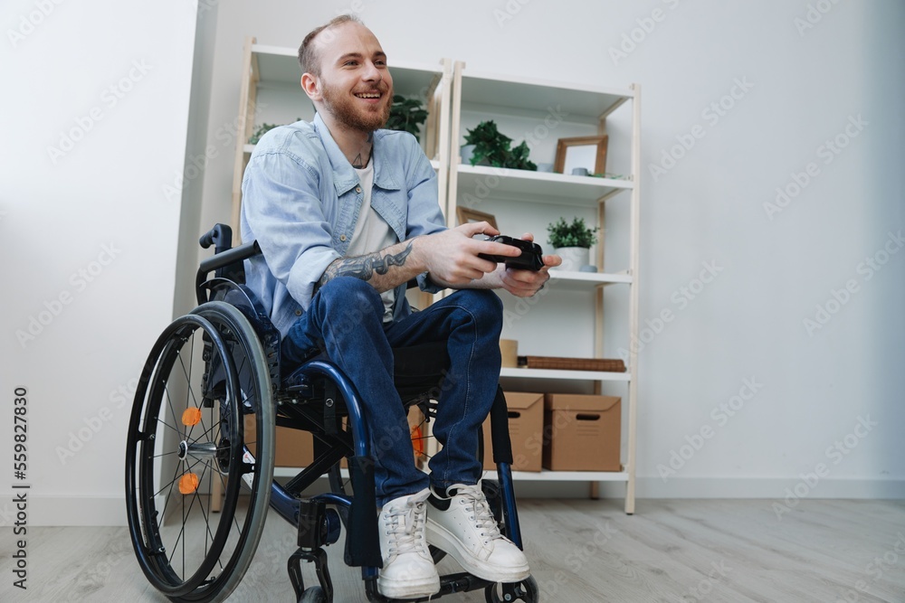A man in a wheelchair gamer plays games with a joystick in his hands at ...