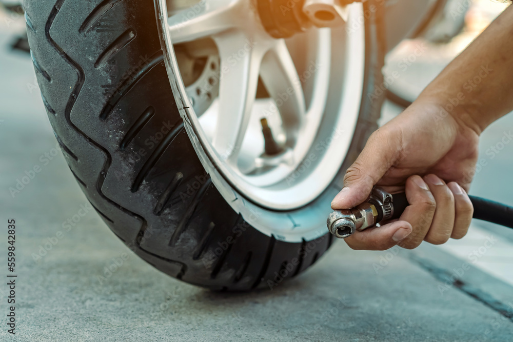 Hands of man check inflator pressure and inflates a tire on motorcycle ...