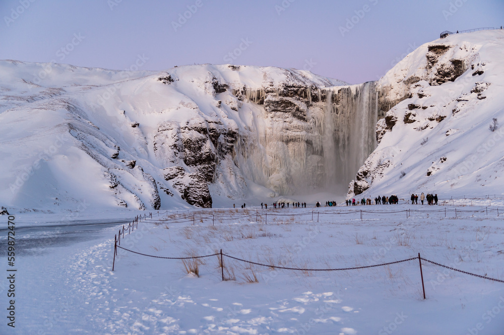 imagen de la cascada de Skógafoss con el entorno nevado, y una capa de ...