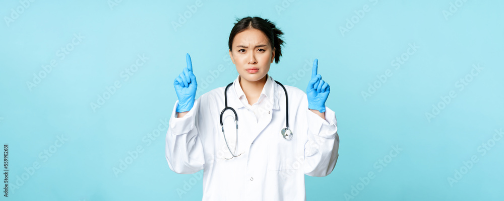 Angry and concerned female doctor, physician pointing fingers up ...