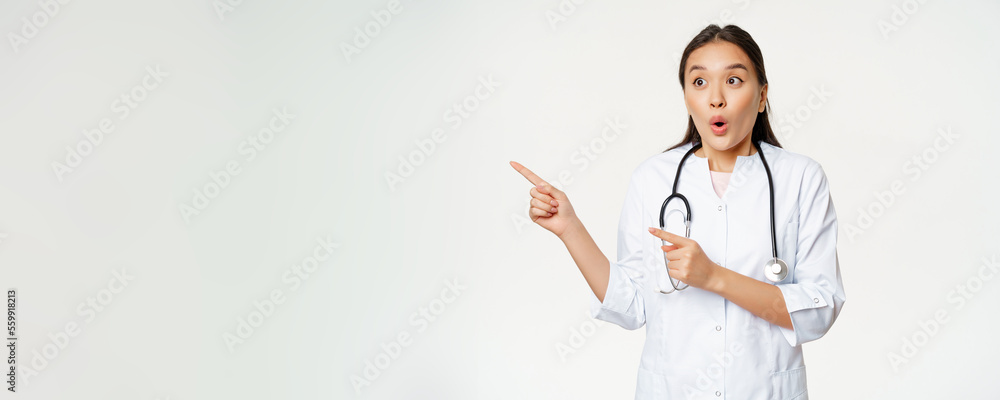 Portrait of enthusiastic female doctor, asian physician pointing and ...