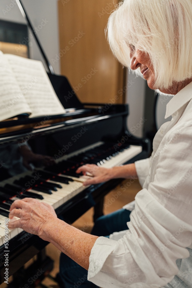 Older Woman Studying Piano With Music Sheets On A Grand Piano Stock Older Woman Studying Piano With Music Sheets On A Grand Piano Stock