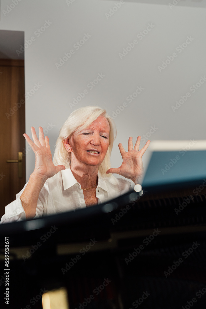Frustrated and angry older woman studying piano with music sheets on a ...