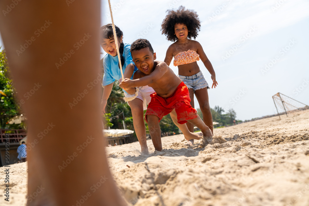 Happy African family on summer holiday vacation. Father, mother and child playing tug of war ...