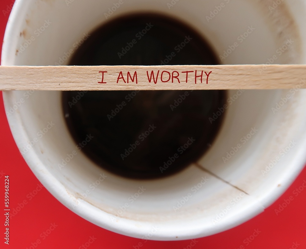 Blur coffee cup and wood stirer with handwritten text I AM WORTHY ...